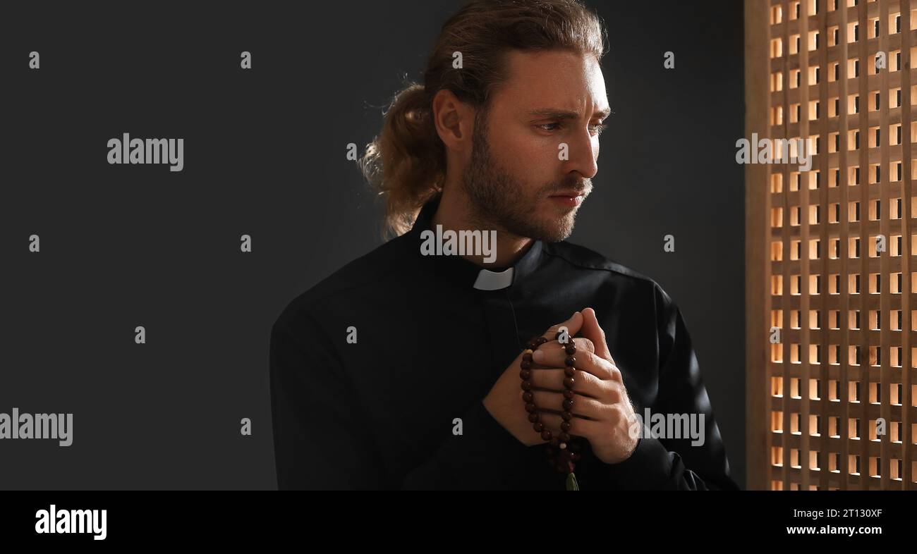 Portrait of male priest in confession booth Stock Photo - Alamy