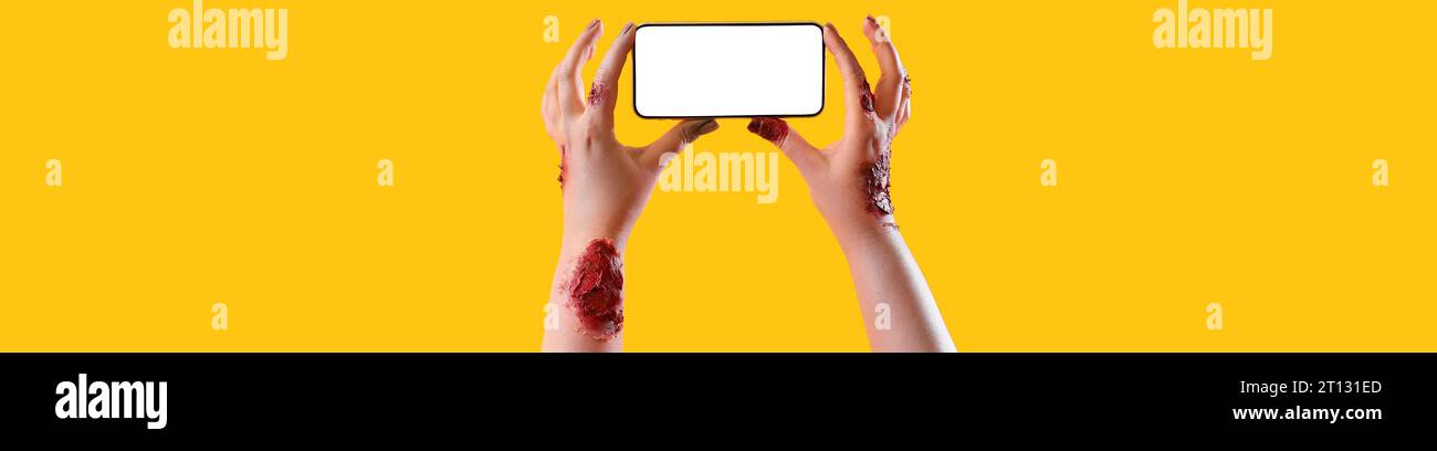 Zombie;s hands holding mobile phone with blank screen on yellow ...