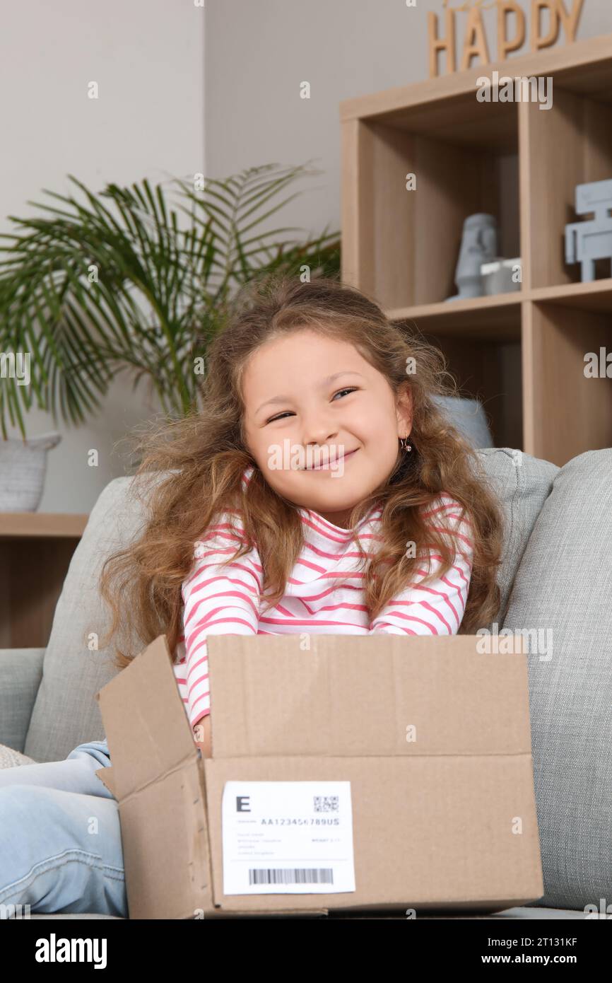 Cute little girl unpacking parcel at home Stock Photo - Alamy