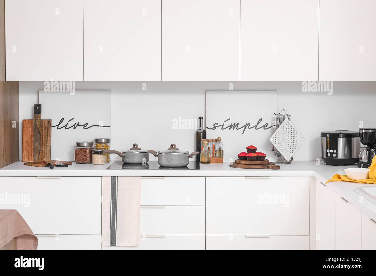 White kitchen counter with electric stove, cooking pots and utensils ...
