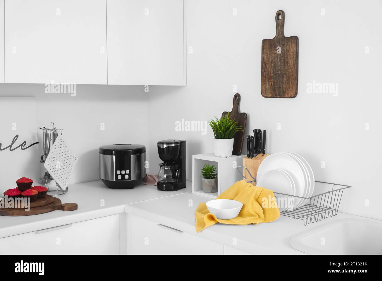 White kitchen counters with coffee machine, multi cooker and utensils ...