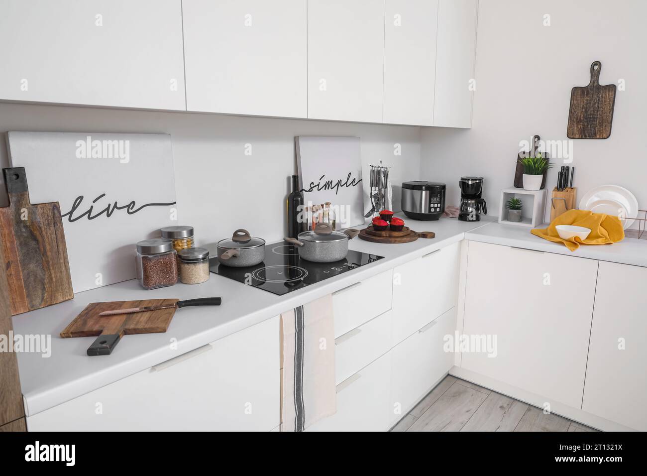 White kitchen counter with electric stove, cooking pots and utensils ...
