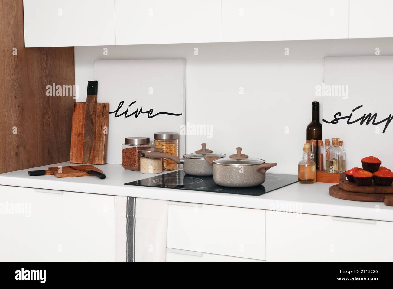 White kitchen counter with electric stove, cooking pots and utensils ...
