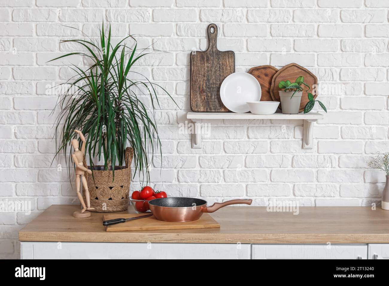 Wooden counters with cutting boards, houseplant, mannequin and frying ...