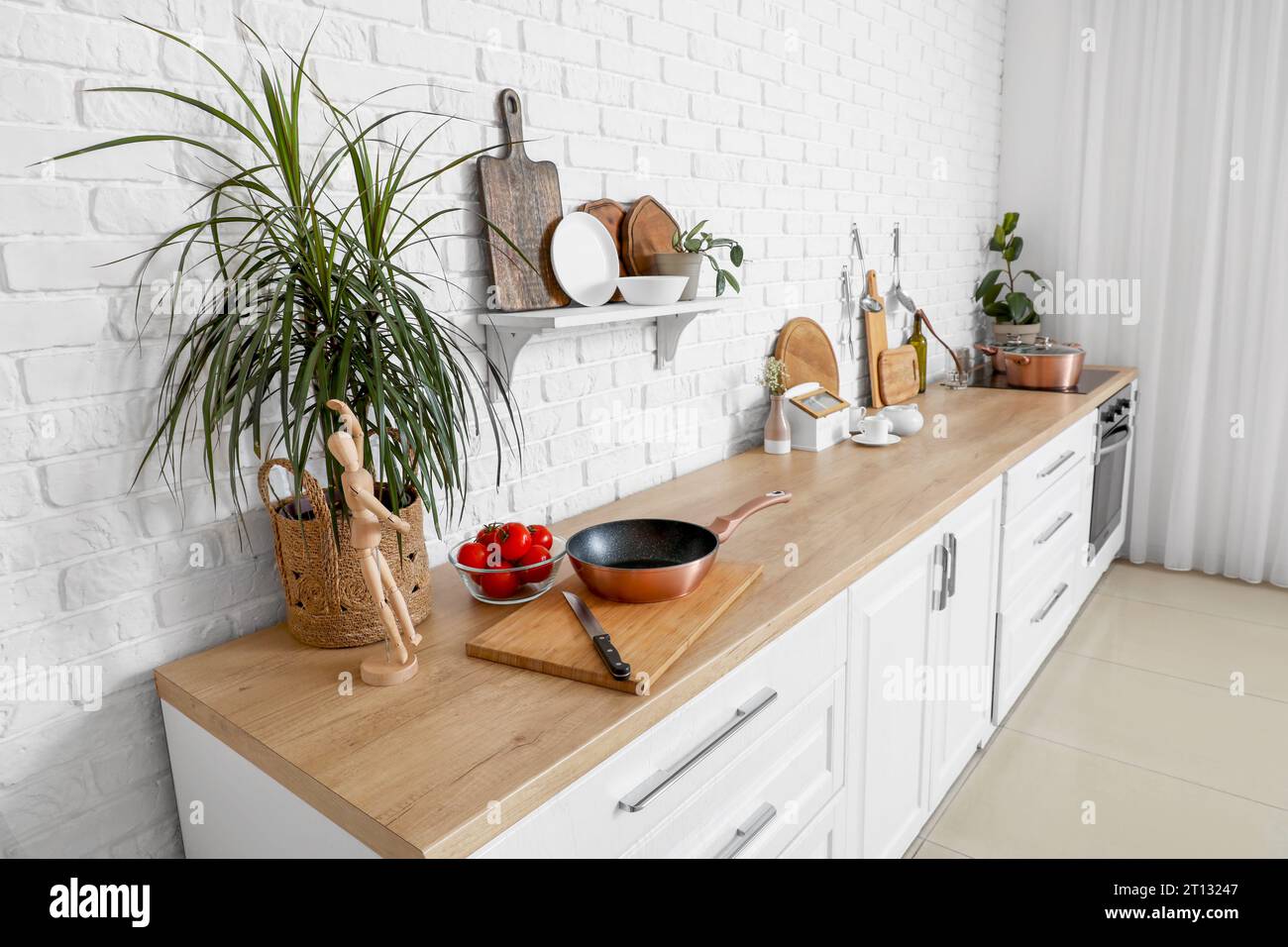 Wooden counter with cutting boards, houseplant, mannequin and frying ...
