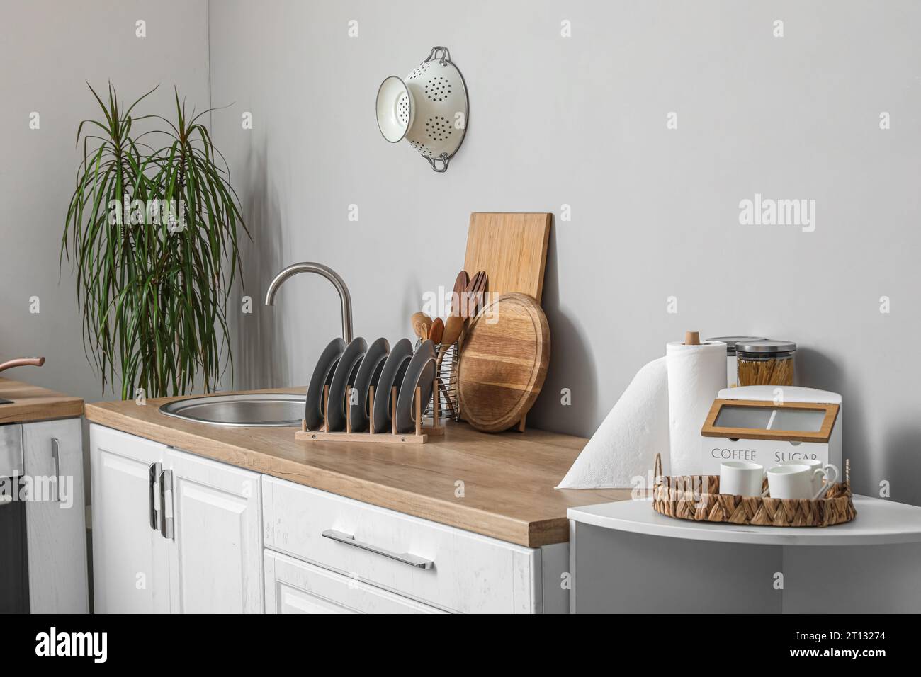 White kitchen counters with cutting boards, plate rack, sink and ...