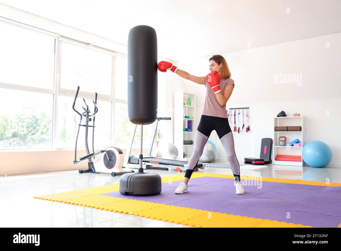 Young woman training with punching bag in gym. Concept of self defense ...