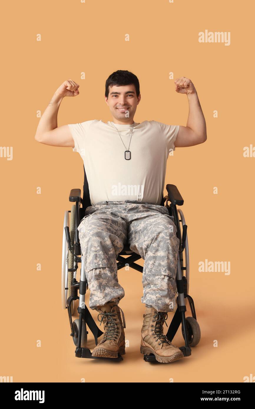 Young soldier in wheelchair showing muscles on beige background Stock ...