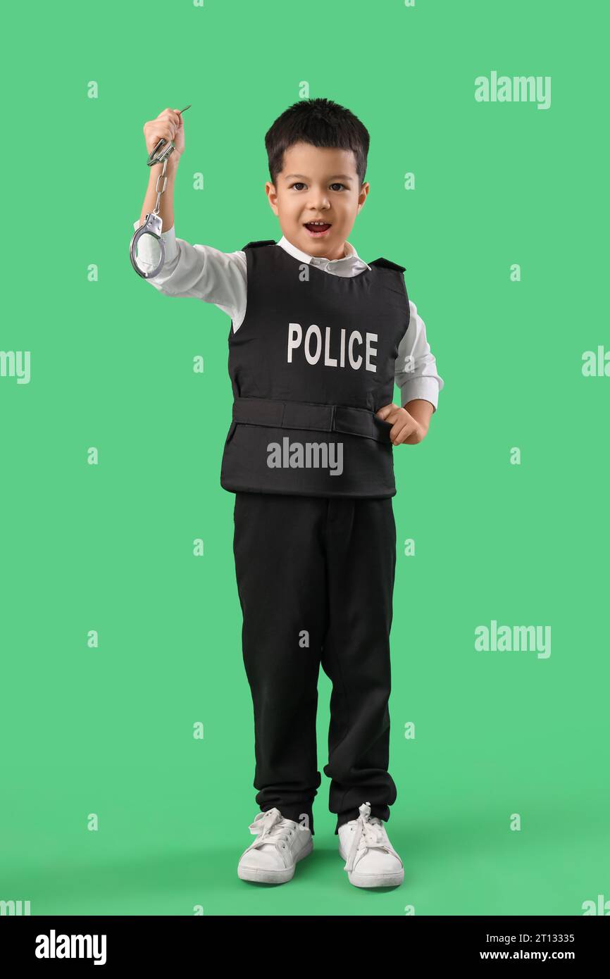 Cute little police officer with handcuffs on green background Stock ...