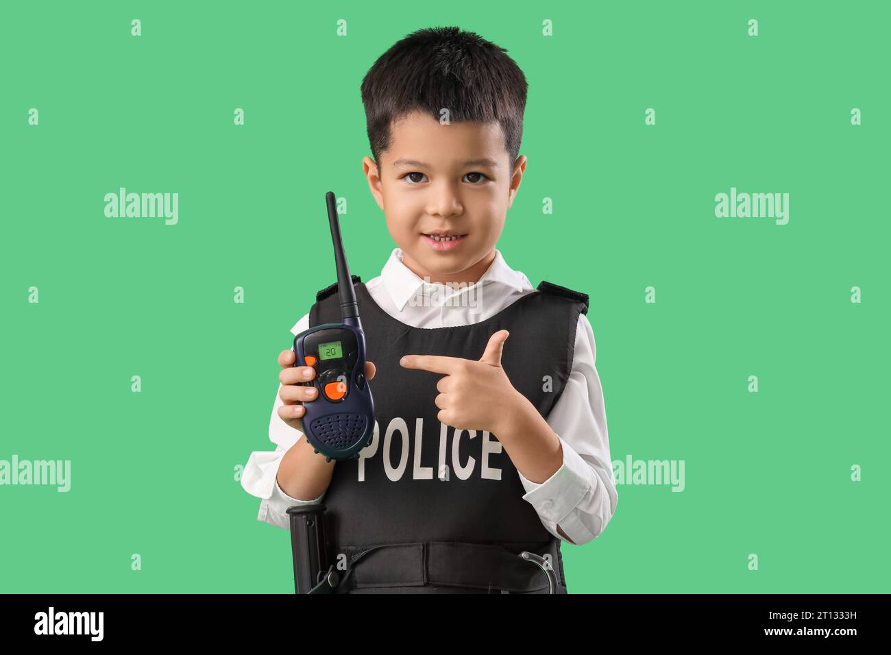 Cute little police officer pointing at radio transmitter on green ...
