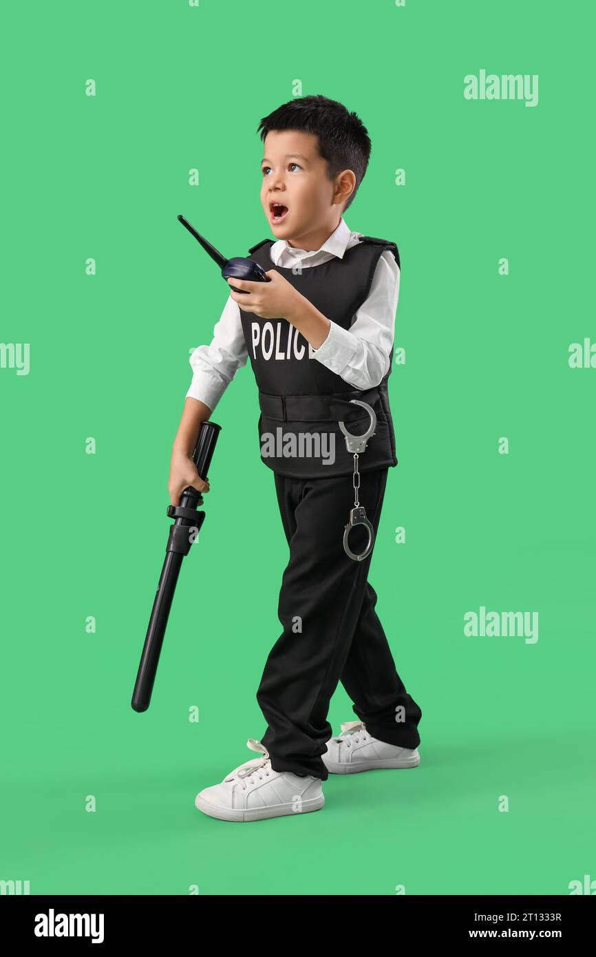 Cute little police officer with radio transmitter and baton on green ...