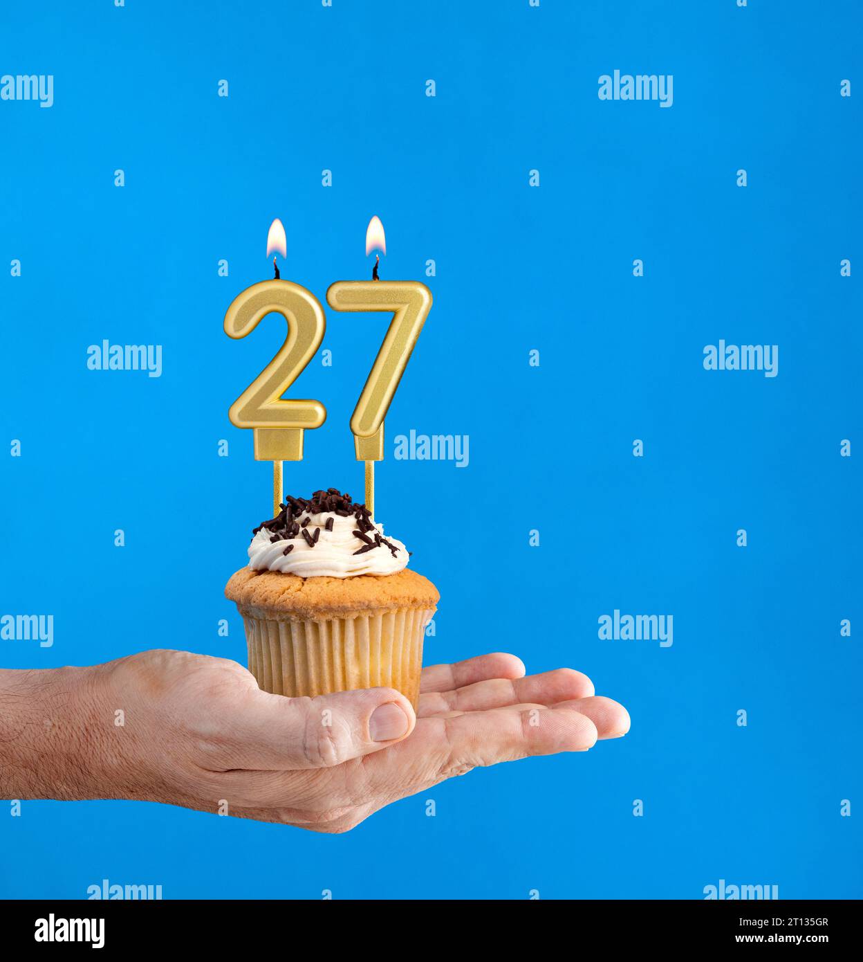 Hand delivering birthday cupcake - Candle number 27 on blue background ...