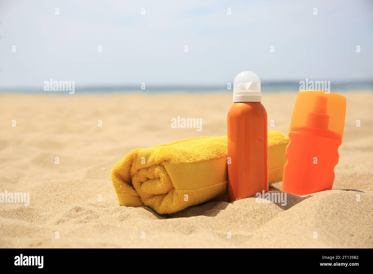 Sunscreens and rolled towel on sandy beach, space for text. Sun ...