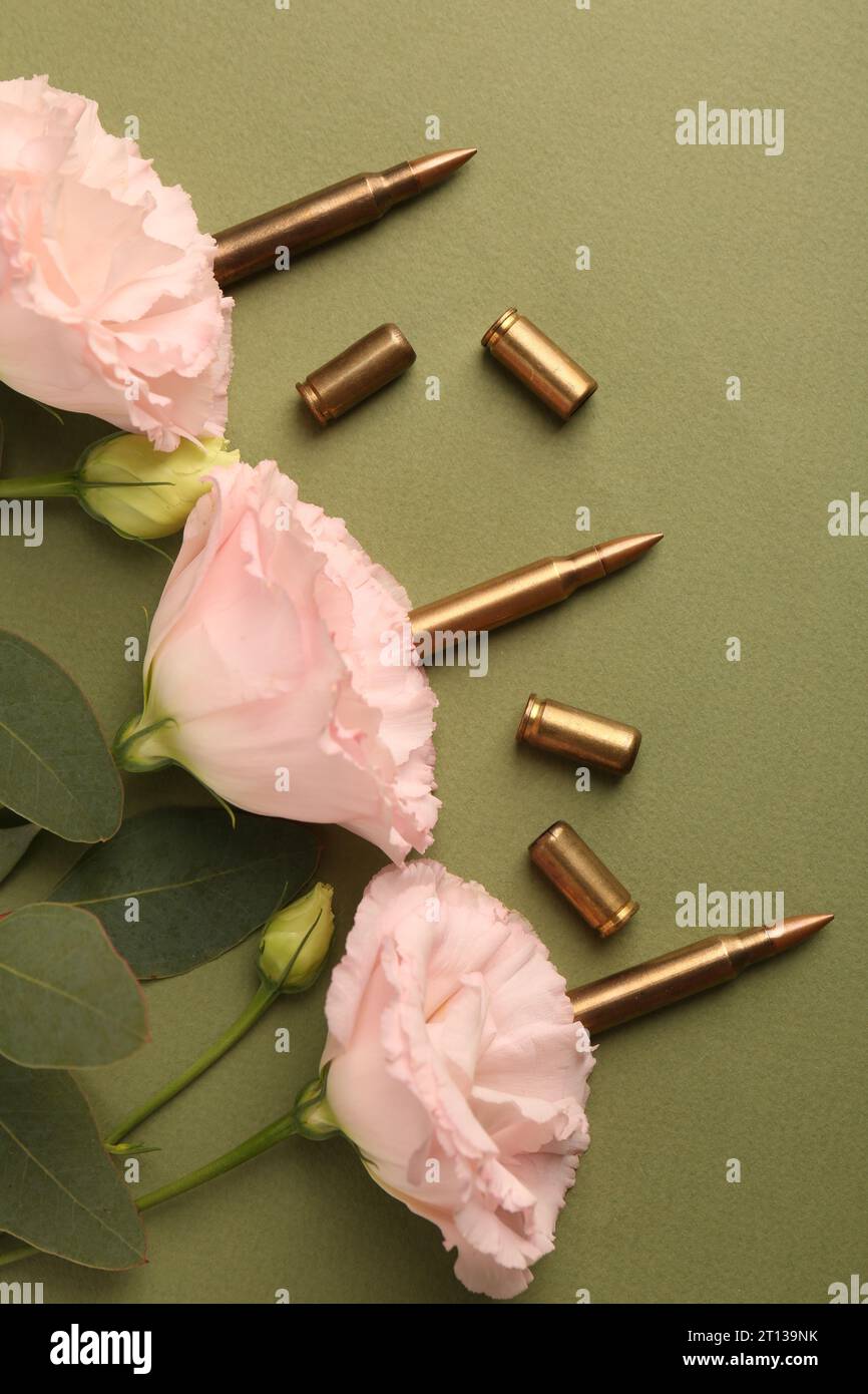 Bullets, cartridge cases and beautiful eustoma flowers on green ...