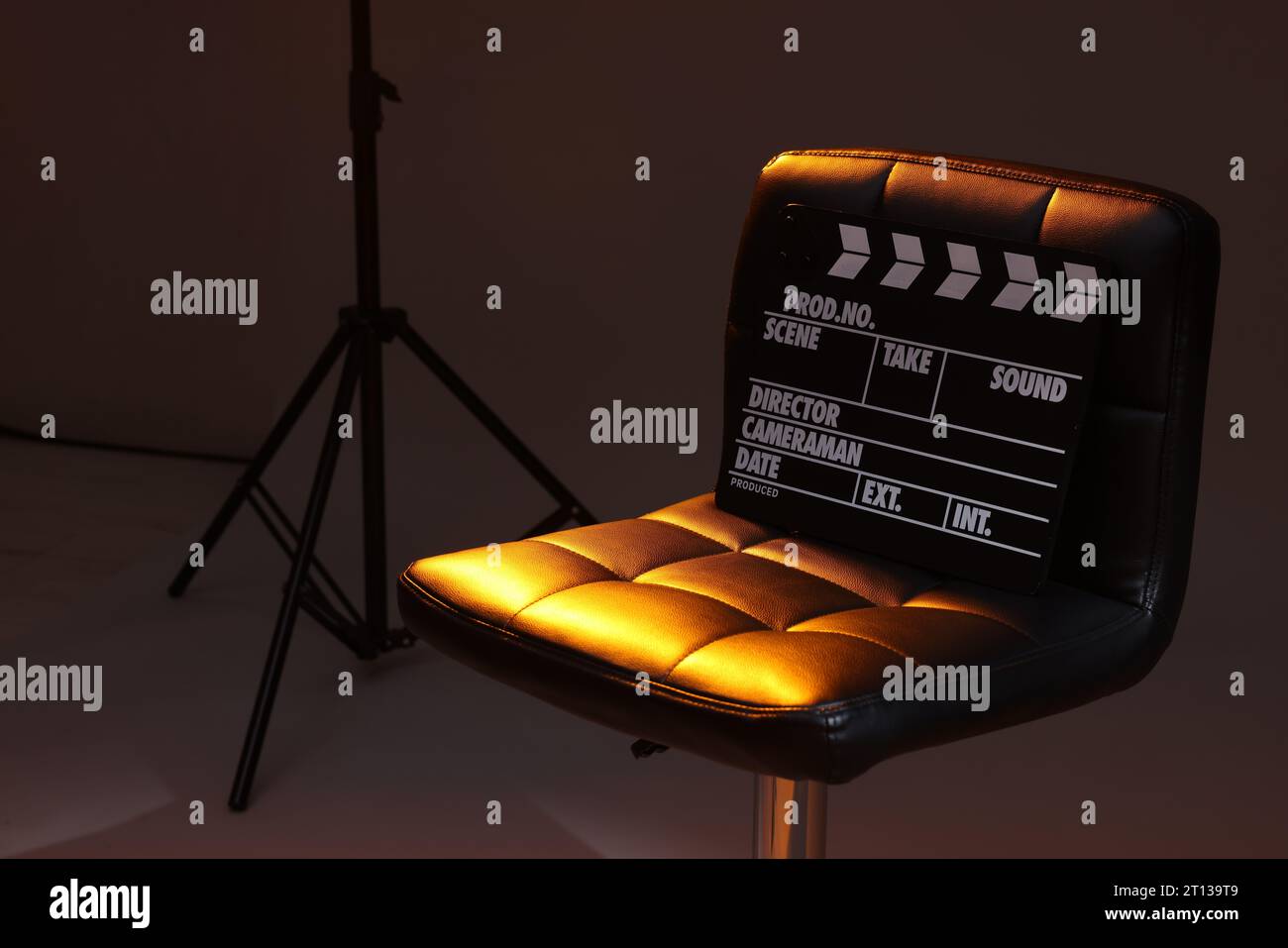 Casting call. Chair and clapperboard in modern studio, closeup. Space ...