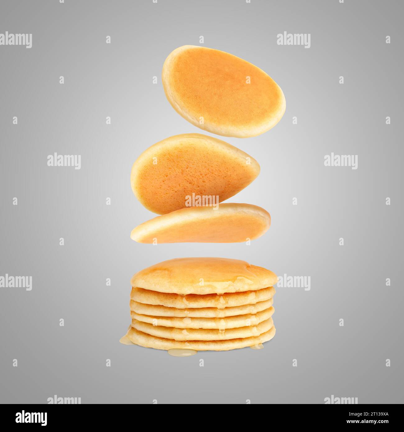 Many tasty fresh pancakes falling on light grey background Stock Photo ...