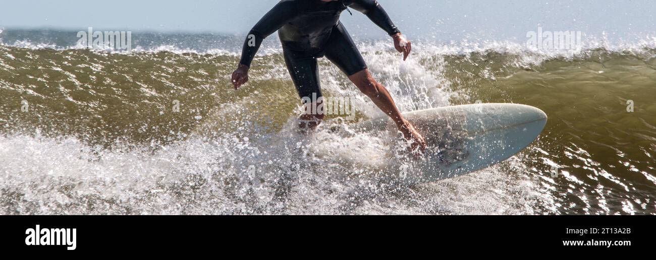 Front view of a man surfing and splashing in rough waves at Gilgo Beach ...