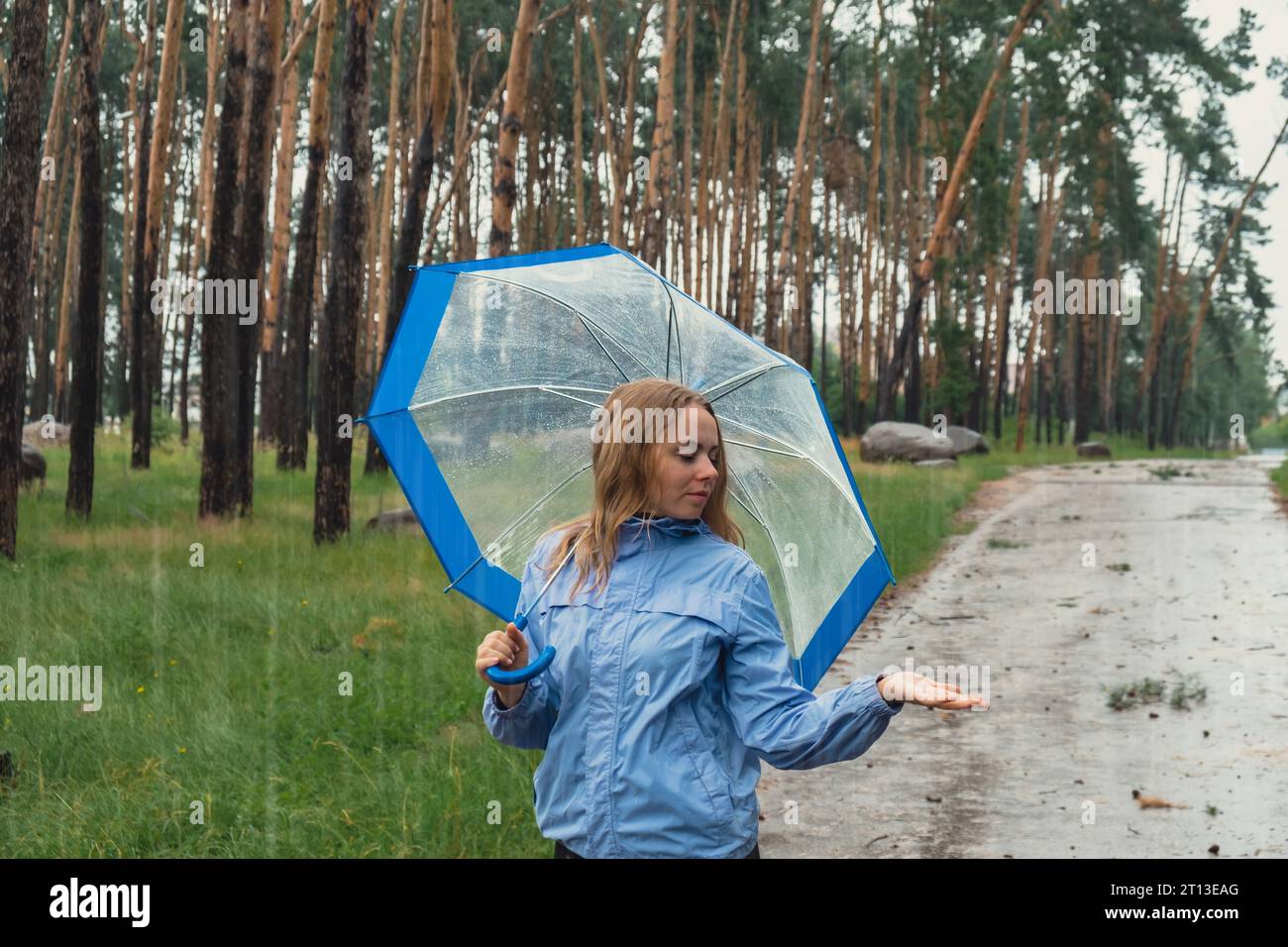 Blonde girl checking the weather under transparent umbrella outside in ...