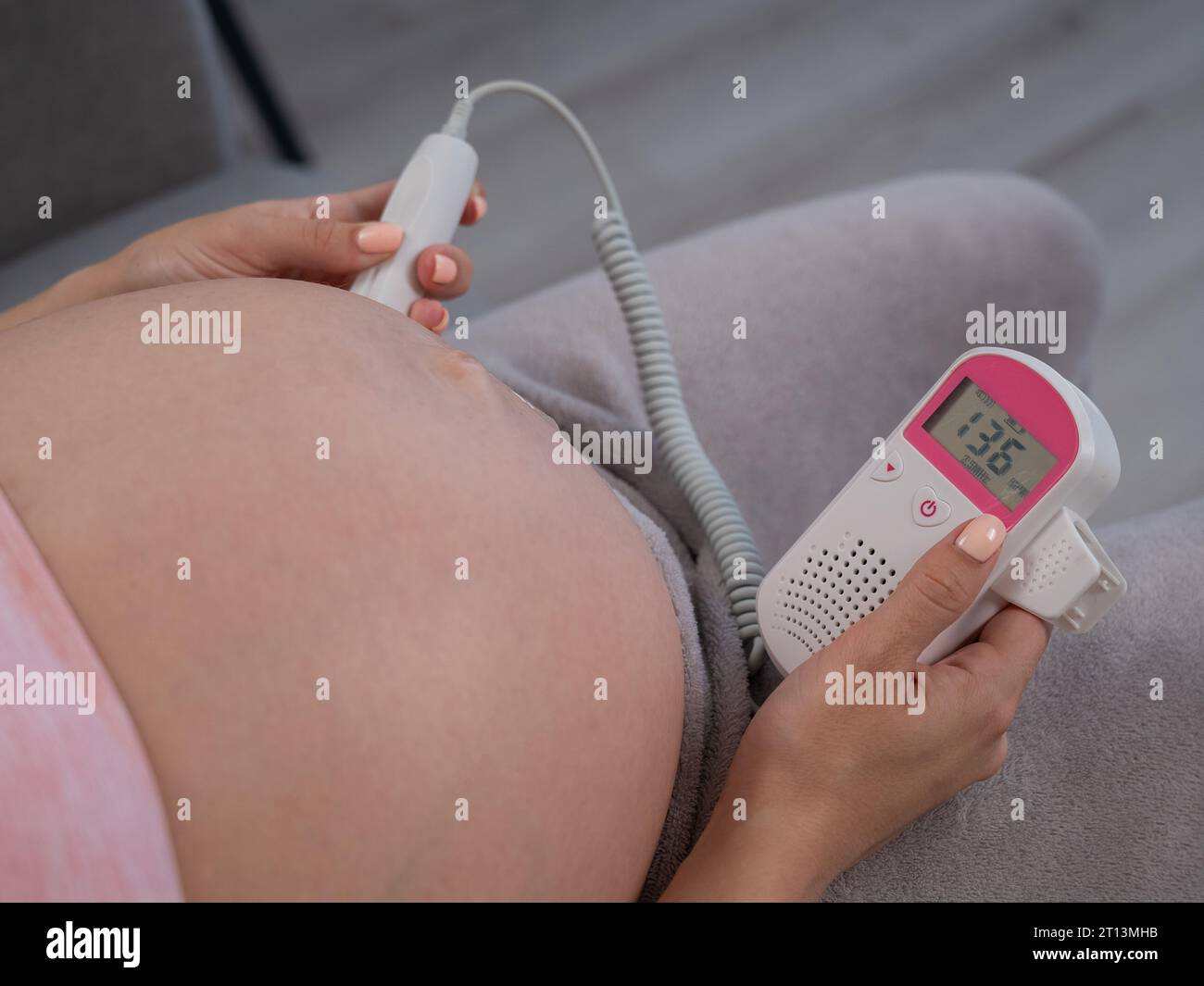 Close-up of a pregnant woman's belly using a home doppler. Normal baby ...