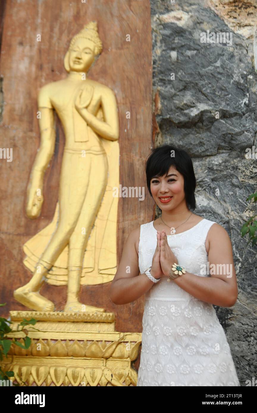 Pretty Asian female standing pose and pay homage in front of the golden ...