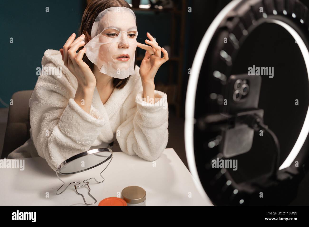 Cheerful vlogger showing beauty sheet mask while recording video and ...