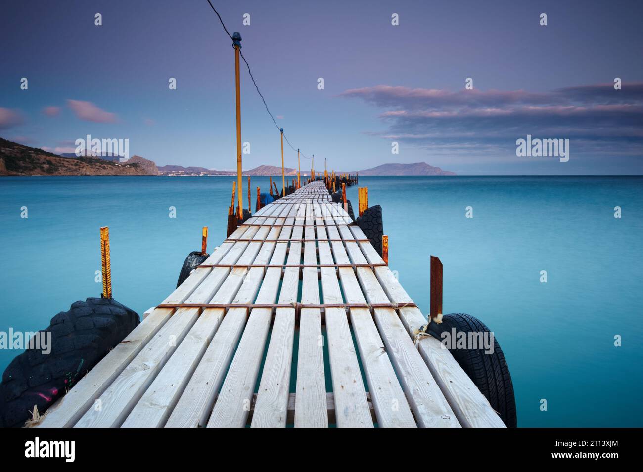 Wooden jetty on sea sunset and sky reflection water. Long exposure ...