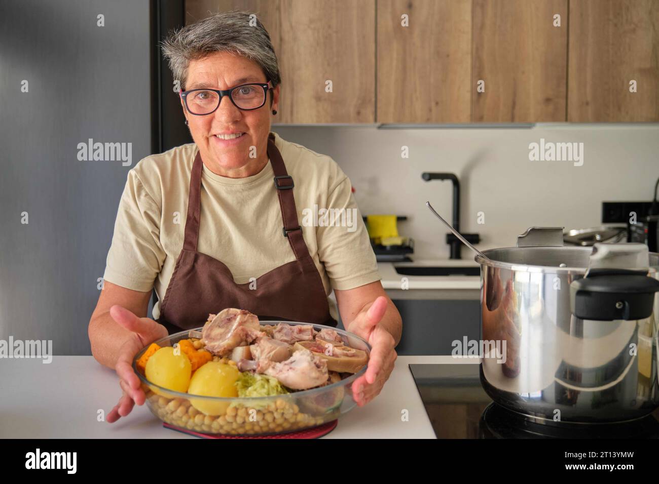 Happy mature Spanish woman showing homemade cocido madrileño, typical ...