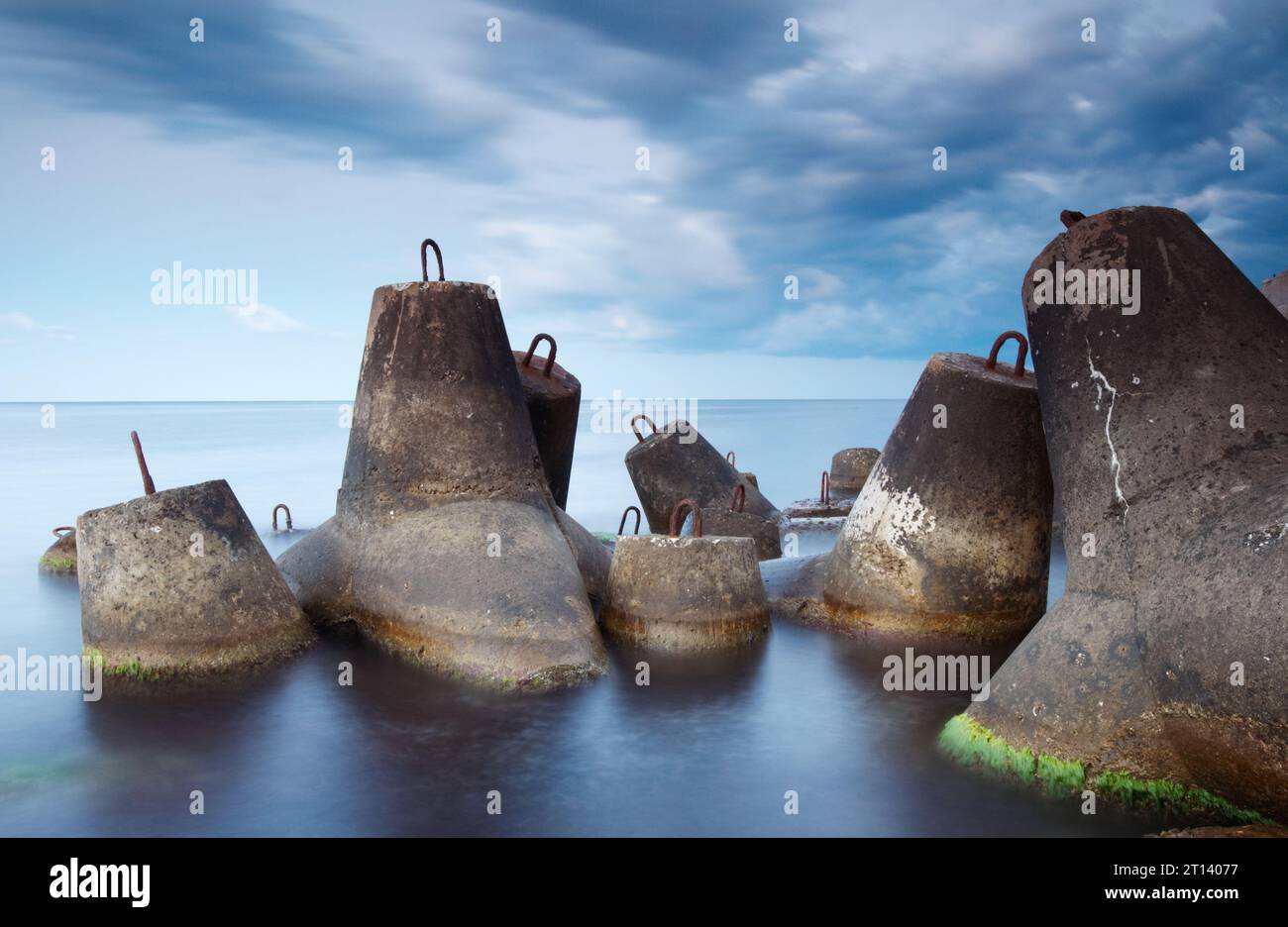 Massive concrete tetrapods form a breakwater with soft bluur sea at ...