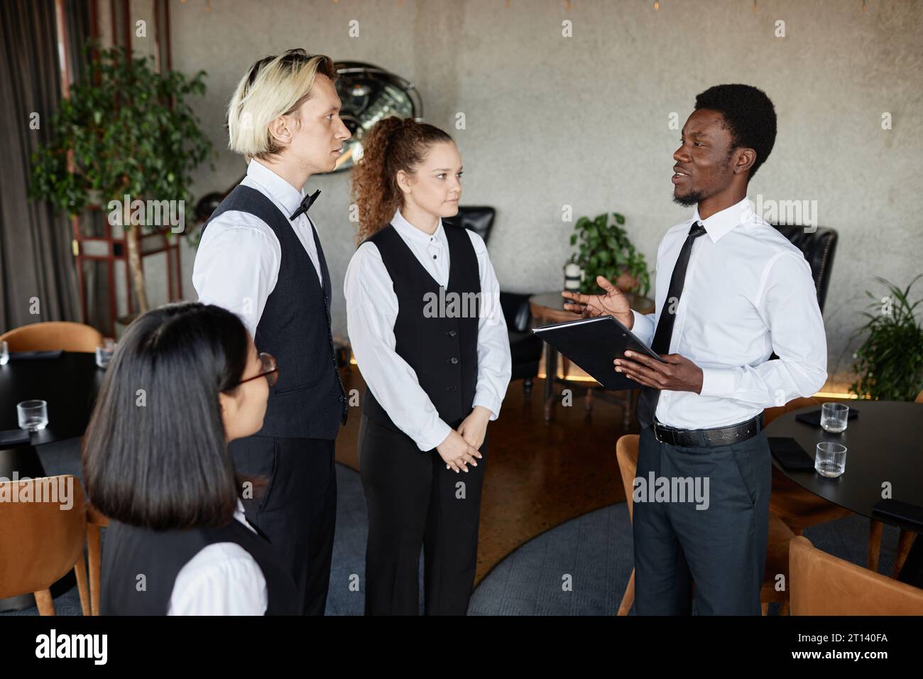 Side view portrait of young Black man as restaurant manager talking to ...