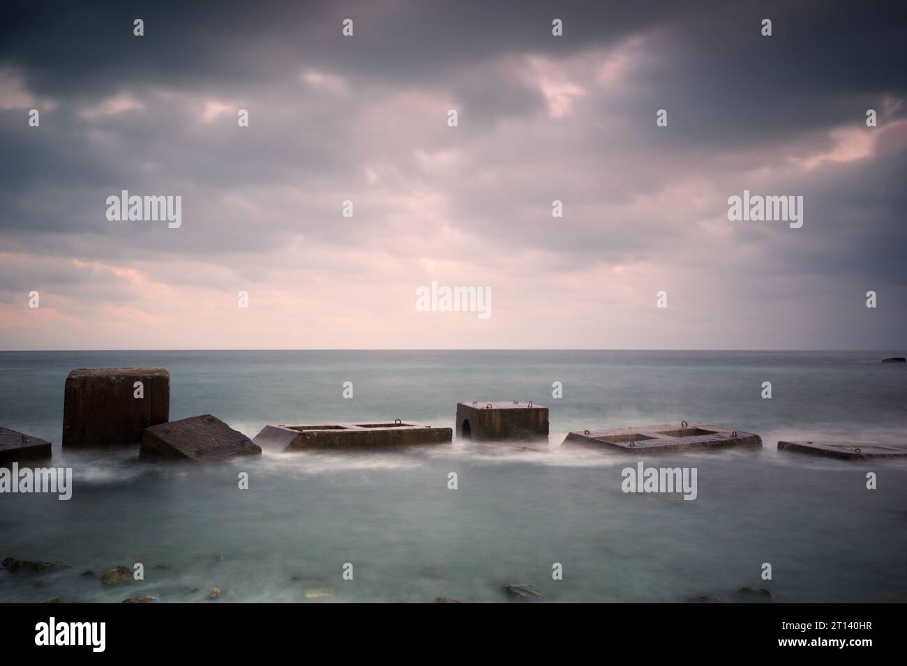 Massive concrete blocks form a breakwater with soft blur sea at night ...