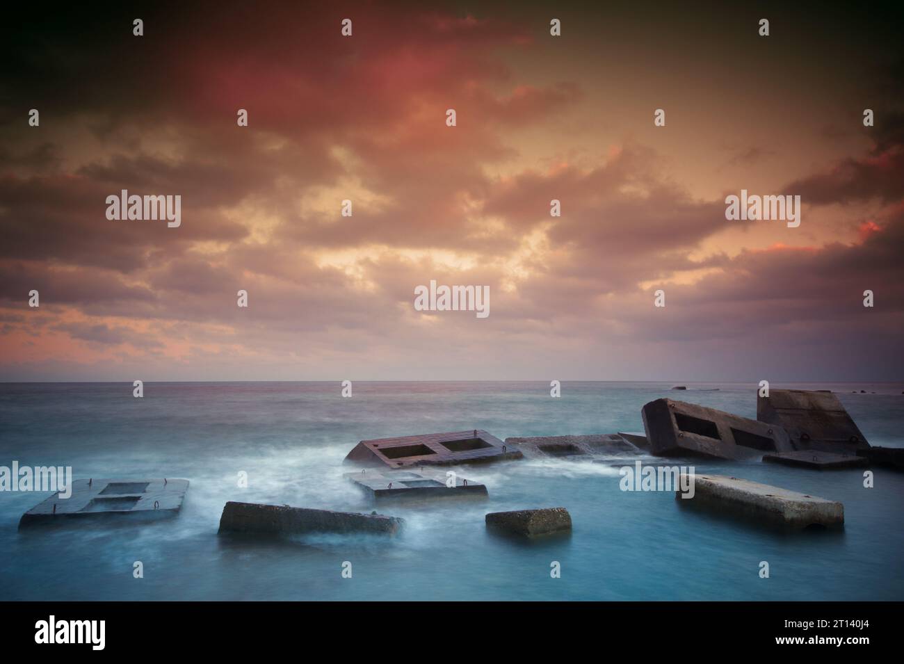 Massive concrete blocks form a breakwater with soft blur sea at night ...