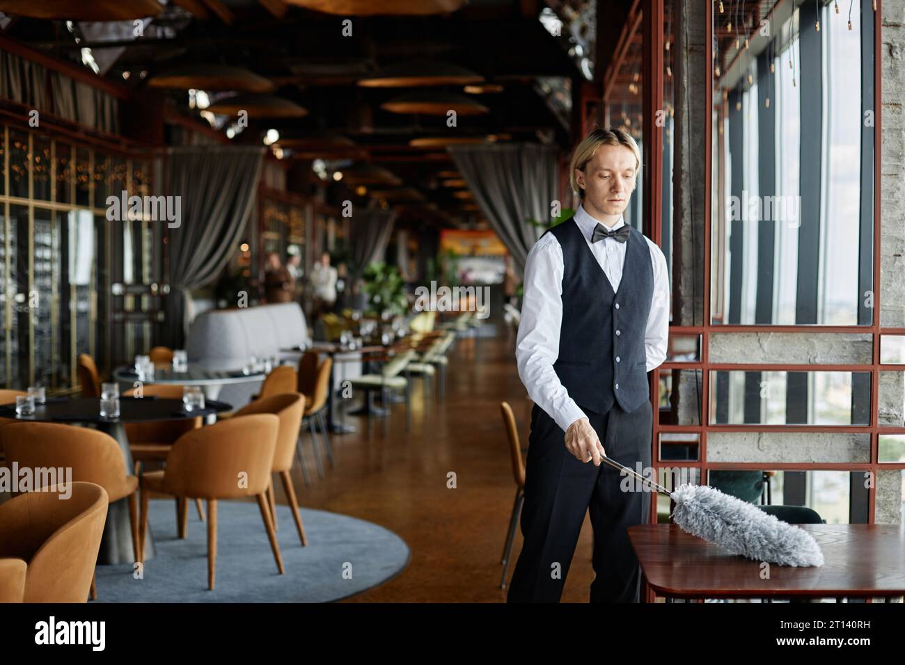 Portrait of elegant young man wearing tuxedo uniform cleaning with ...