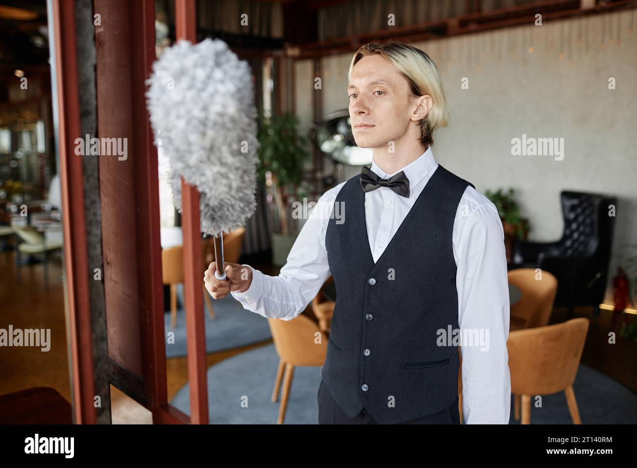 Waist up portrait of elegant young man wearing bowtie cleaning with ...