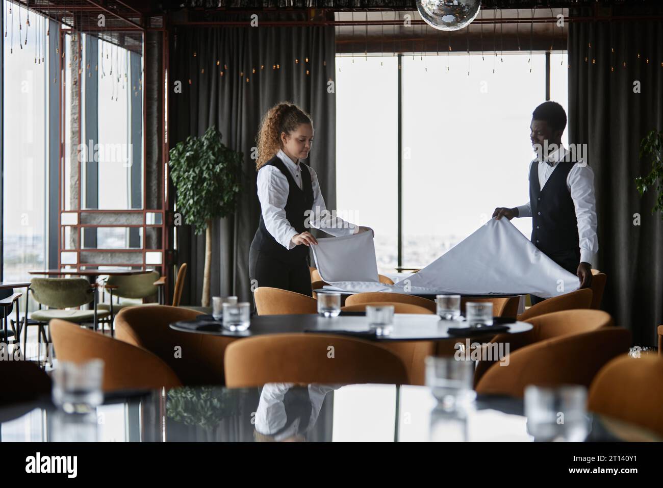 Side view portrait of two elegant waiters setting tables in luxury ...