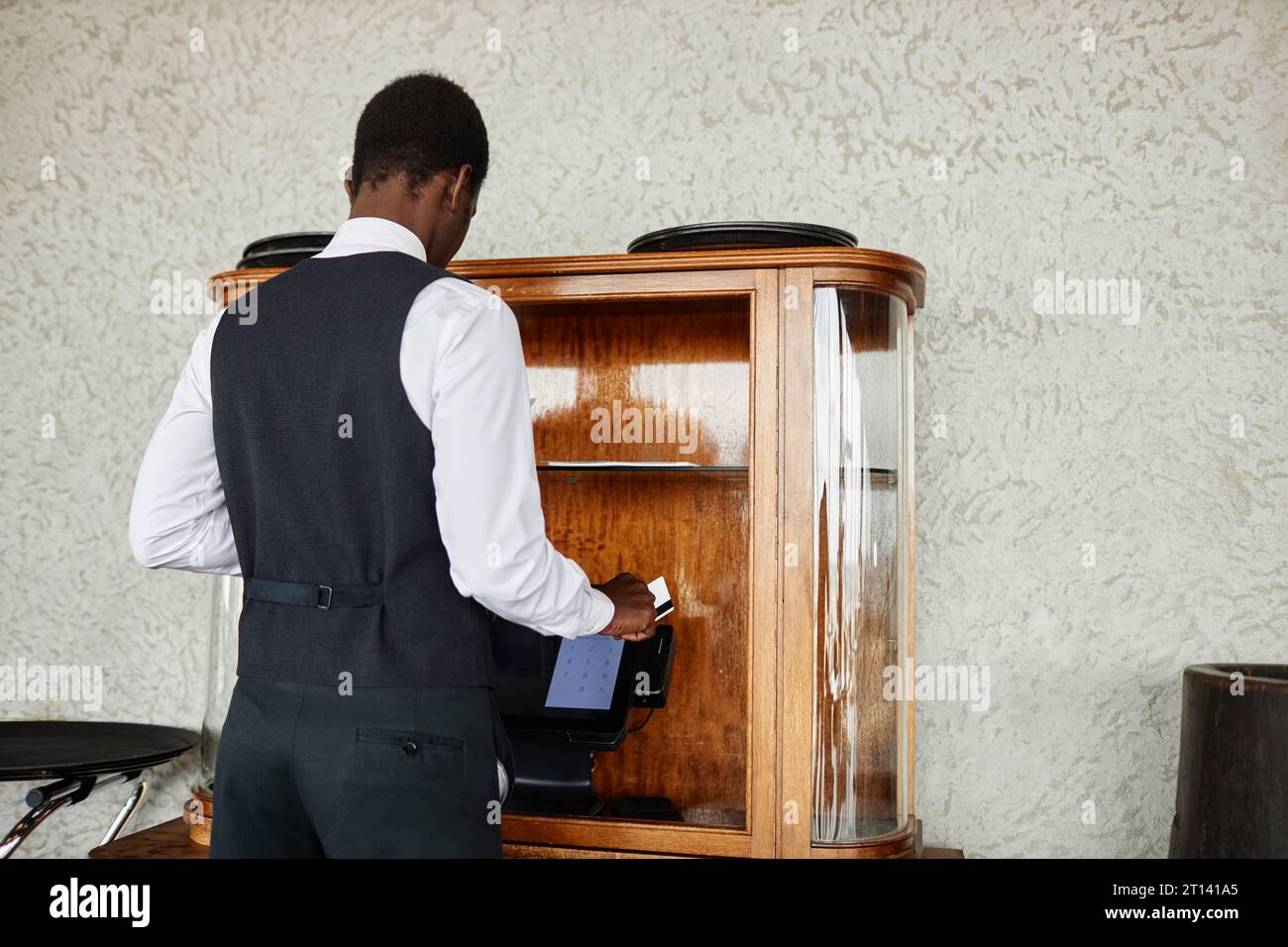 Back view of waiter using computer system in restaurant and putting ...
