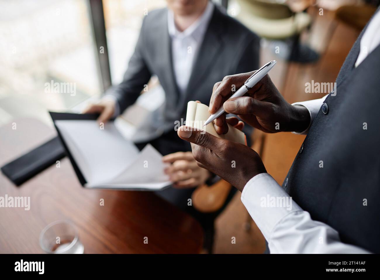 Close up of male waiter holding notepad and taking order from guests in ...