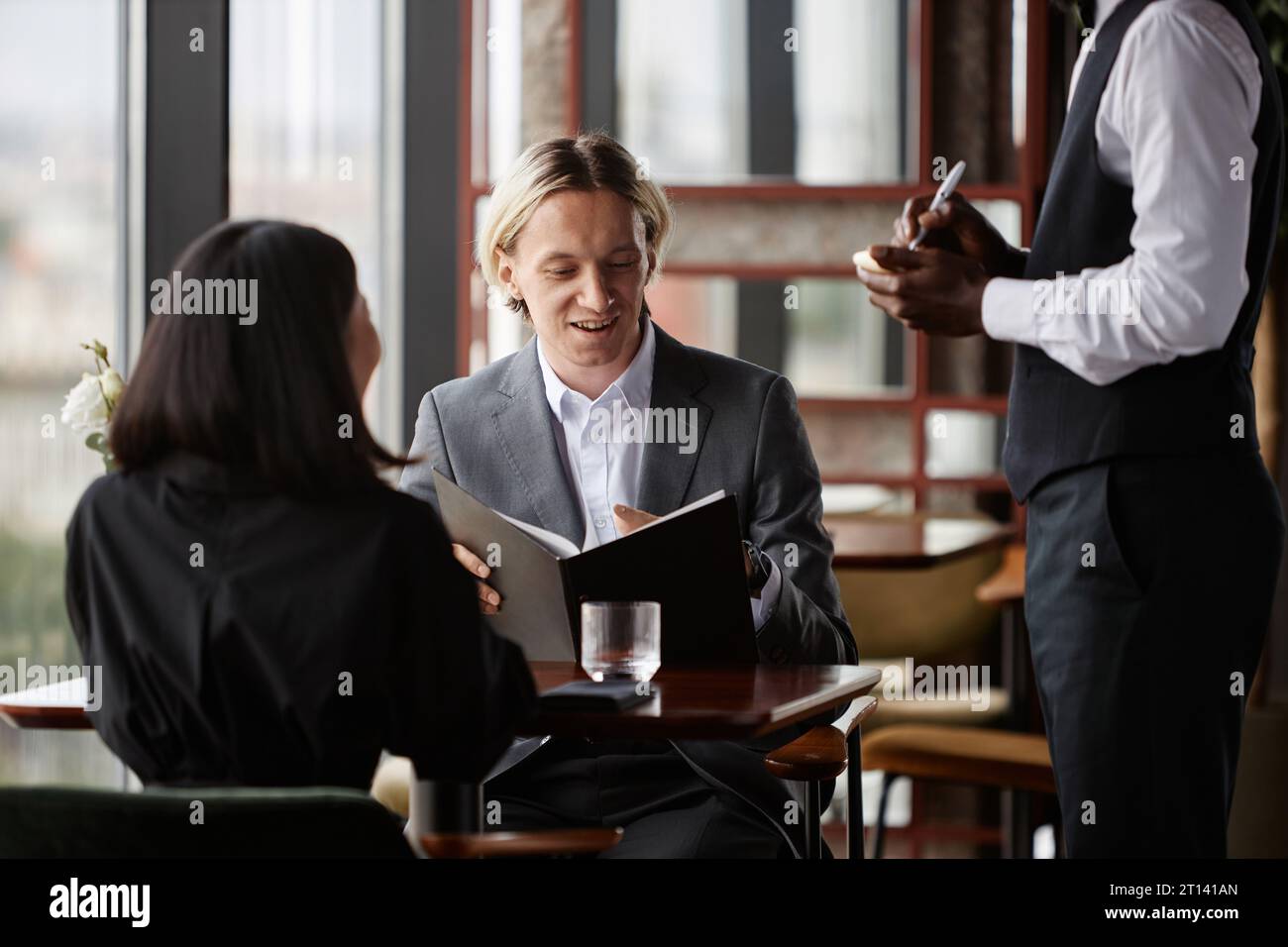Portrait of adult couple ordering food in luxury restaurant with focus ...