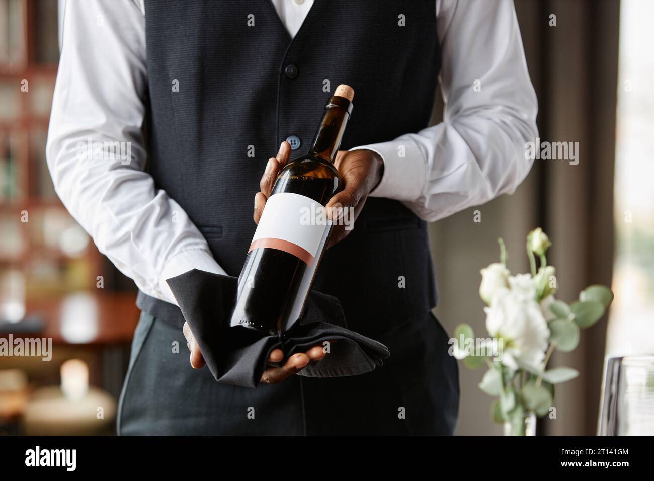 Close up of unrecognizable waiter presenting bottle of red wine in ...