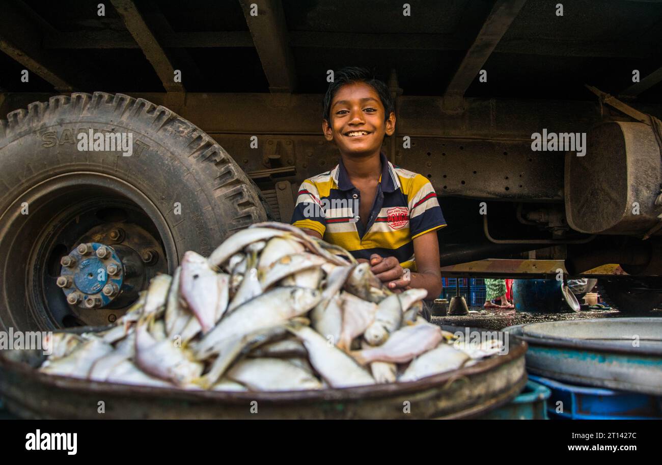 Poor children are cutting fish at a local Fish Market in Barishal ...