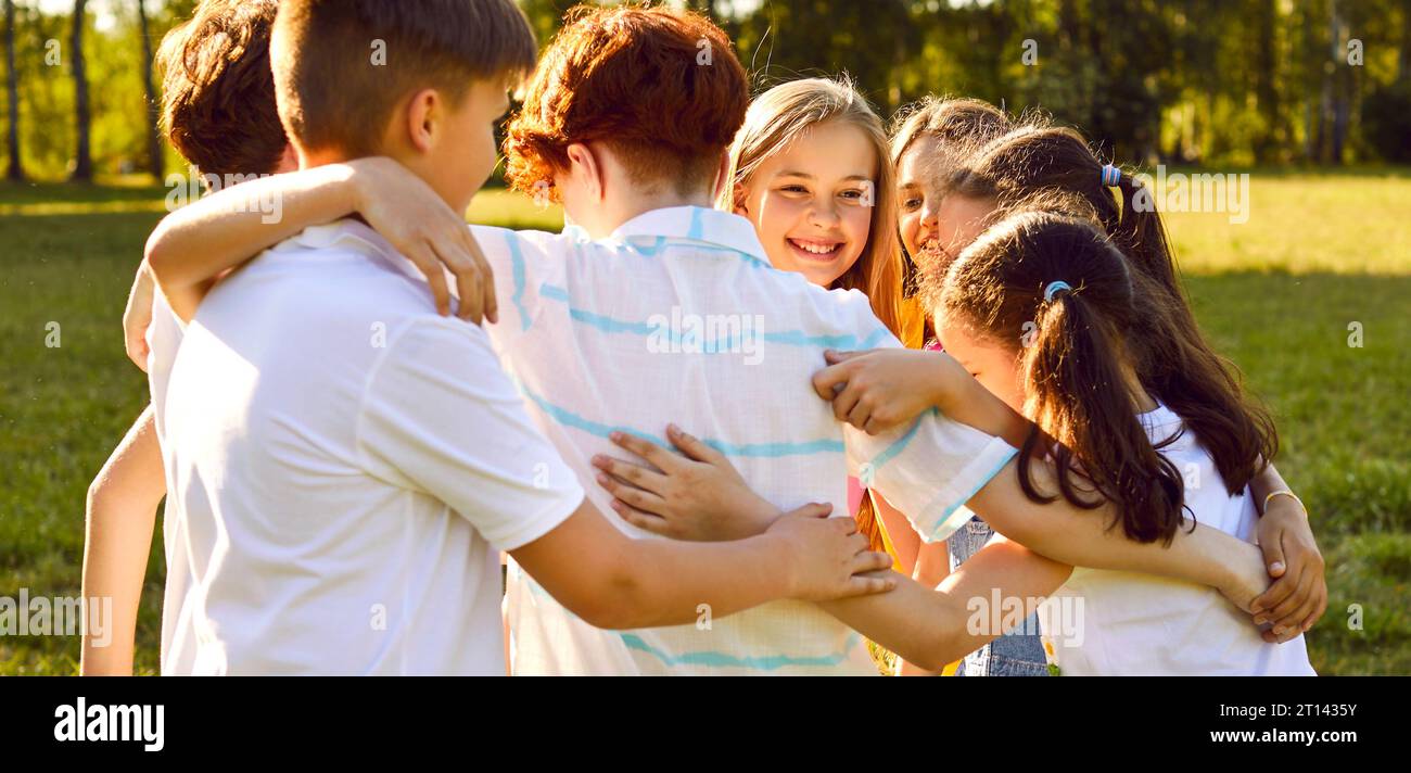 Happy children standing together outdoors hugging and smiling in the ...