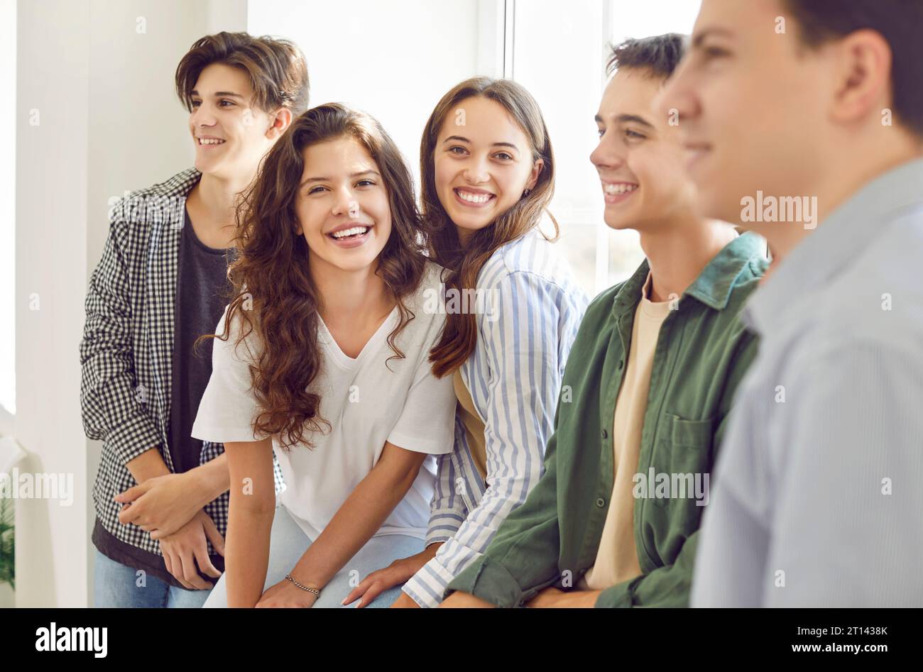 Group of a happy friends high school students standing together and looking cheerful at camera ...