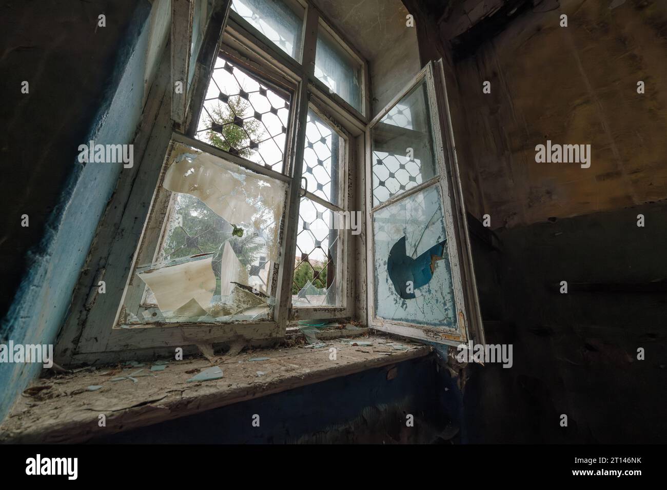 Opened window with shattered glass inside dark room of abandoned ...