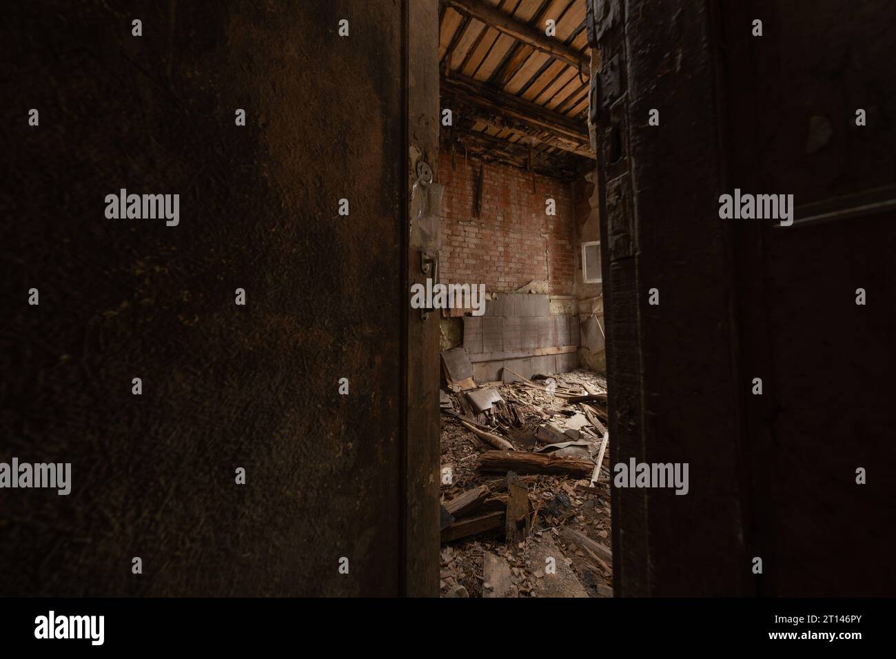 Half opened wooden door leading to weathered destroyed room of ...
