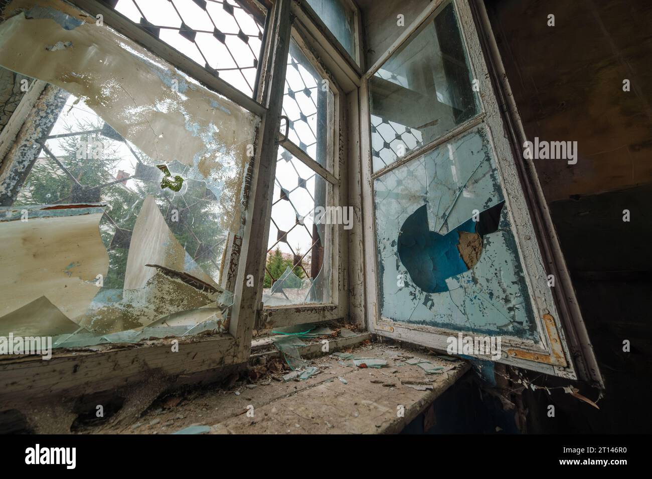 Opened window with shattered glass inside dark room of abandoned ...