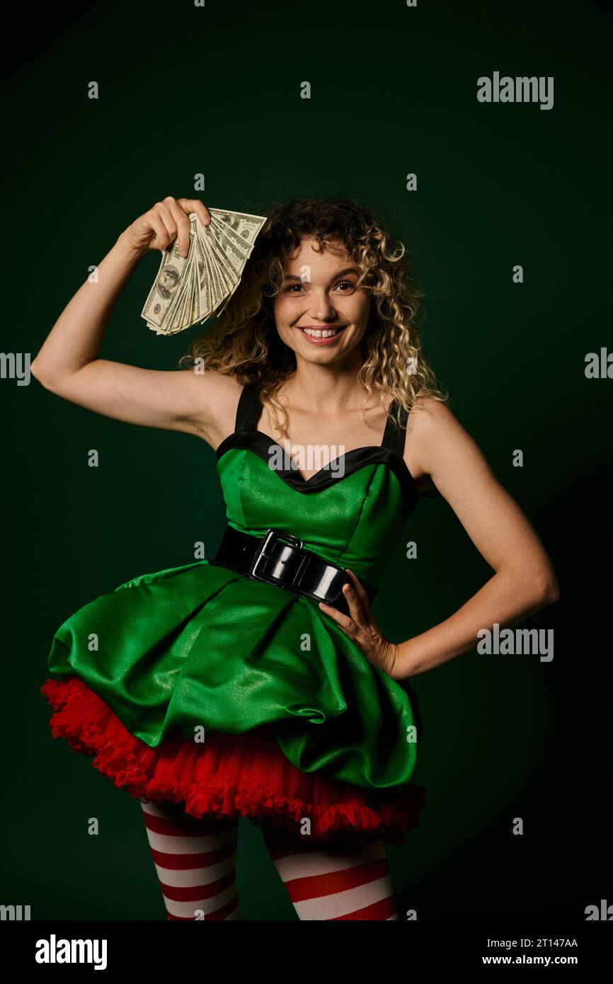 happy curly woman dressed as new year elf with one arm akimbo and with ...