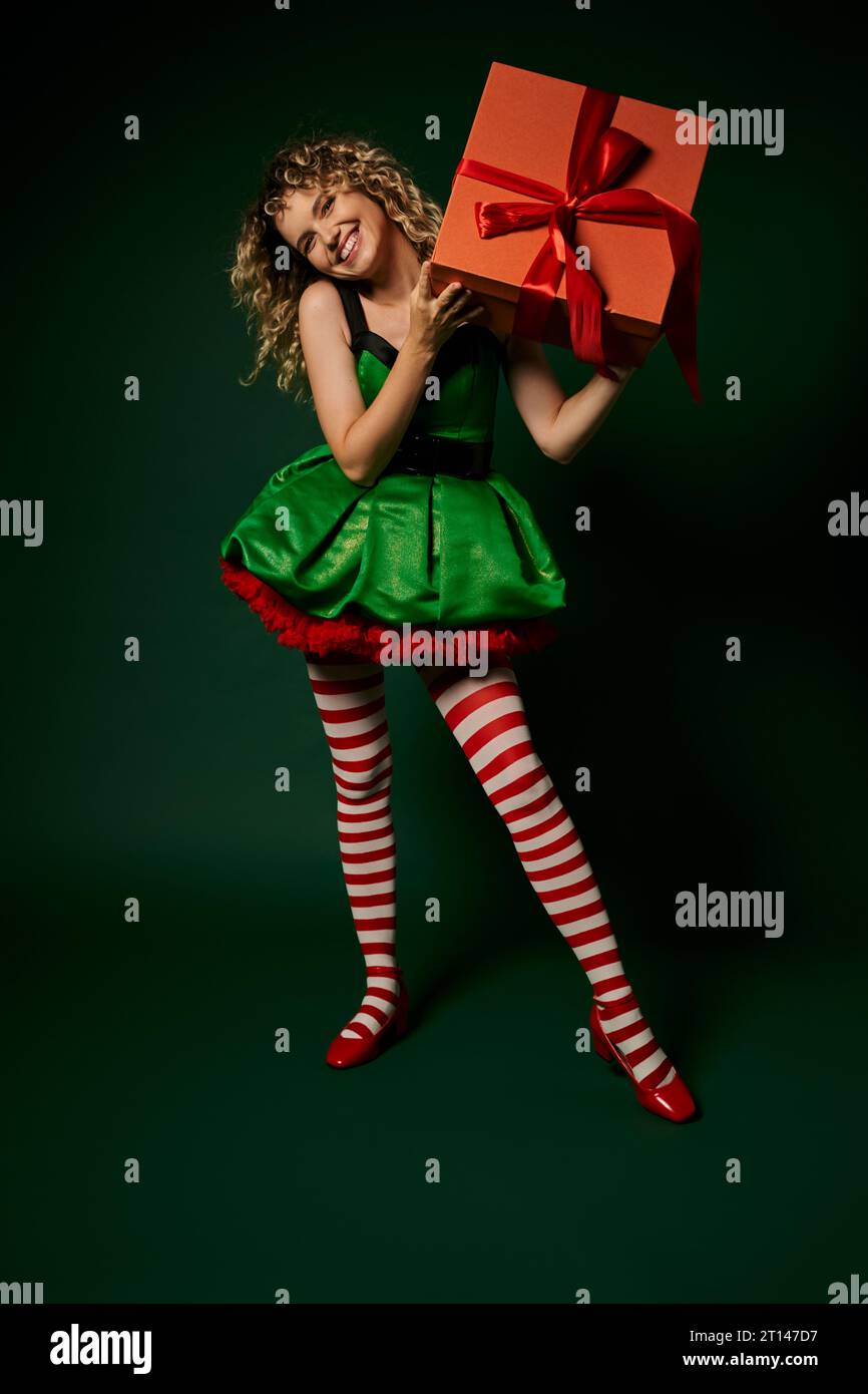 beautiful curly woman in green dress smiling cheerfully and raising ...