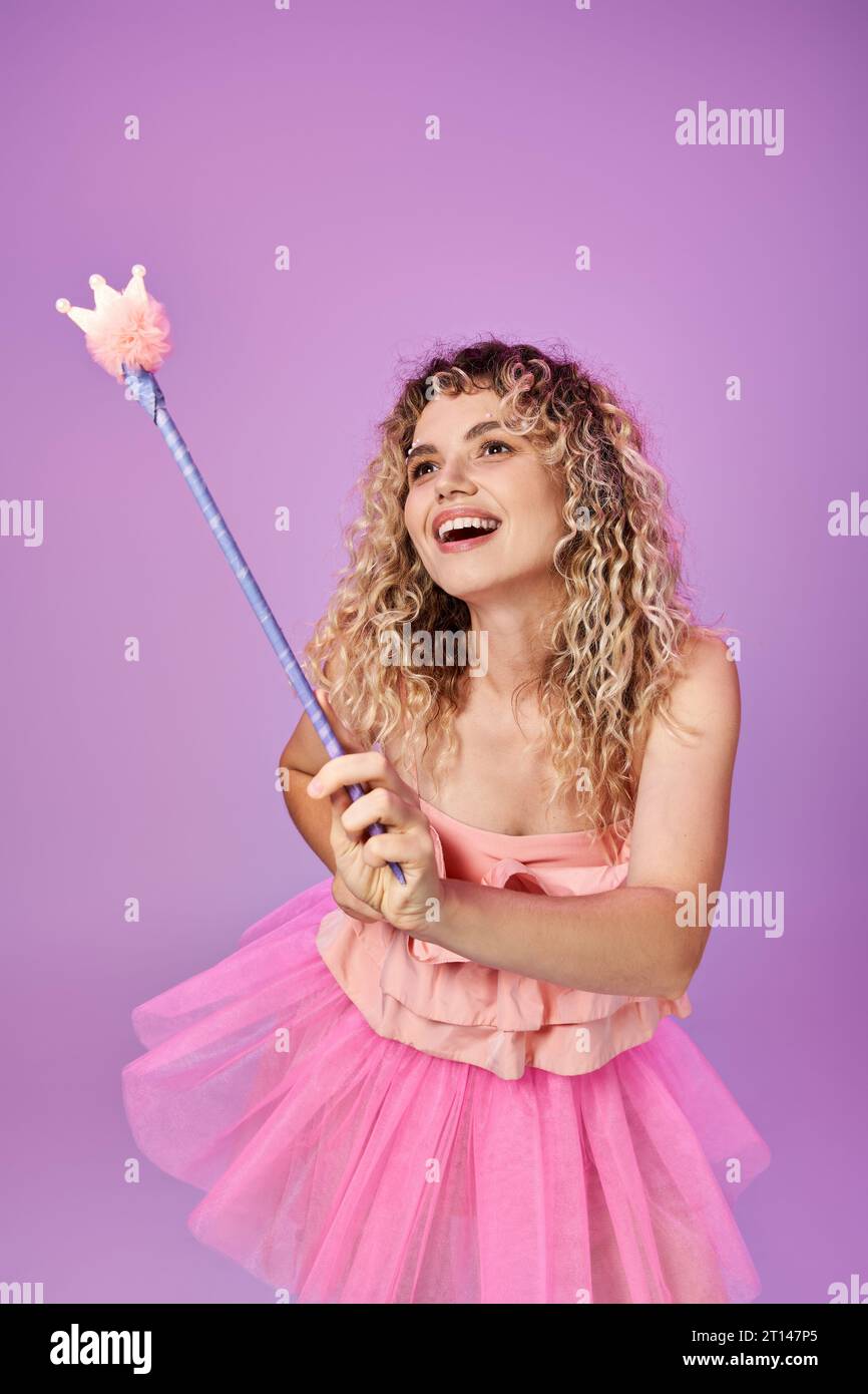beautiful woman in pink dress casting spell with magic wand and looking ...