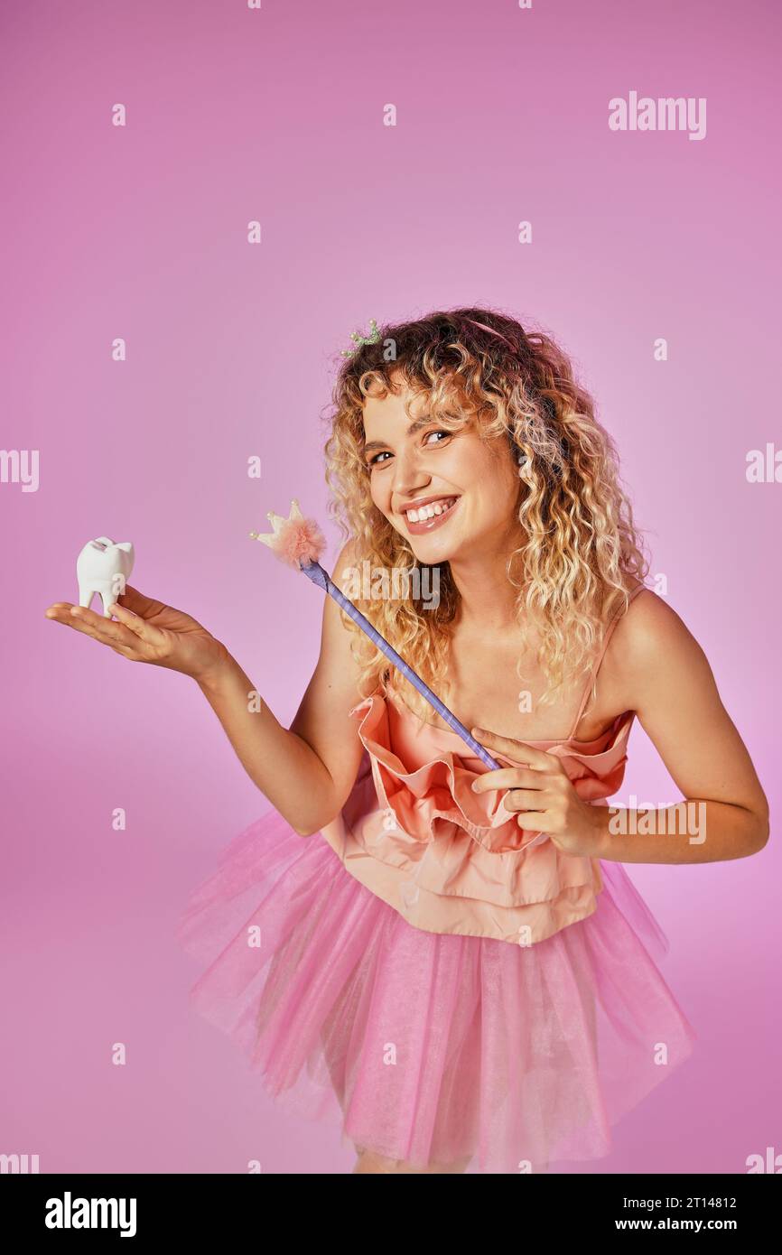 playful lovely blonde woman in pink tooth fairy costume smiling and ...
