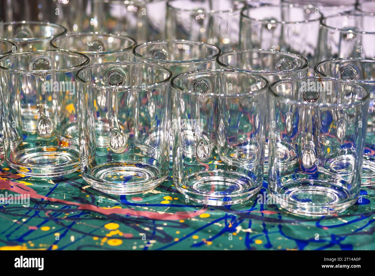 Transparent cups on a color table. It is a lot of glass cups. Empty ...