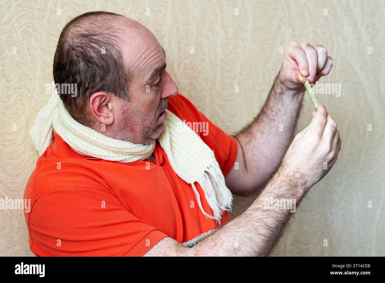 A sick man looks at a thermometer. Patient checking his temperature at ...